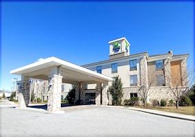 Um hotel moderno com entrada coberta, fachada de pedra e uma placa indicando ser parte da Hampton Inn Express.