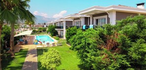 Zona residencial com piscina, cadeiras de descanso e vista para montanhas.