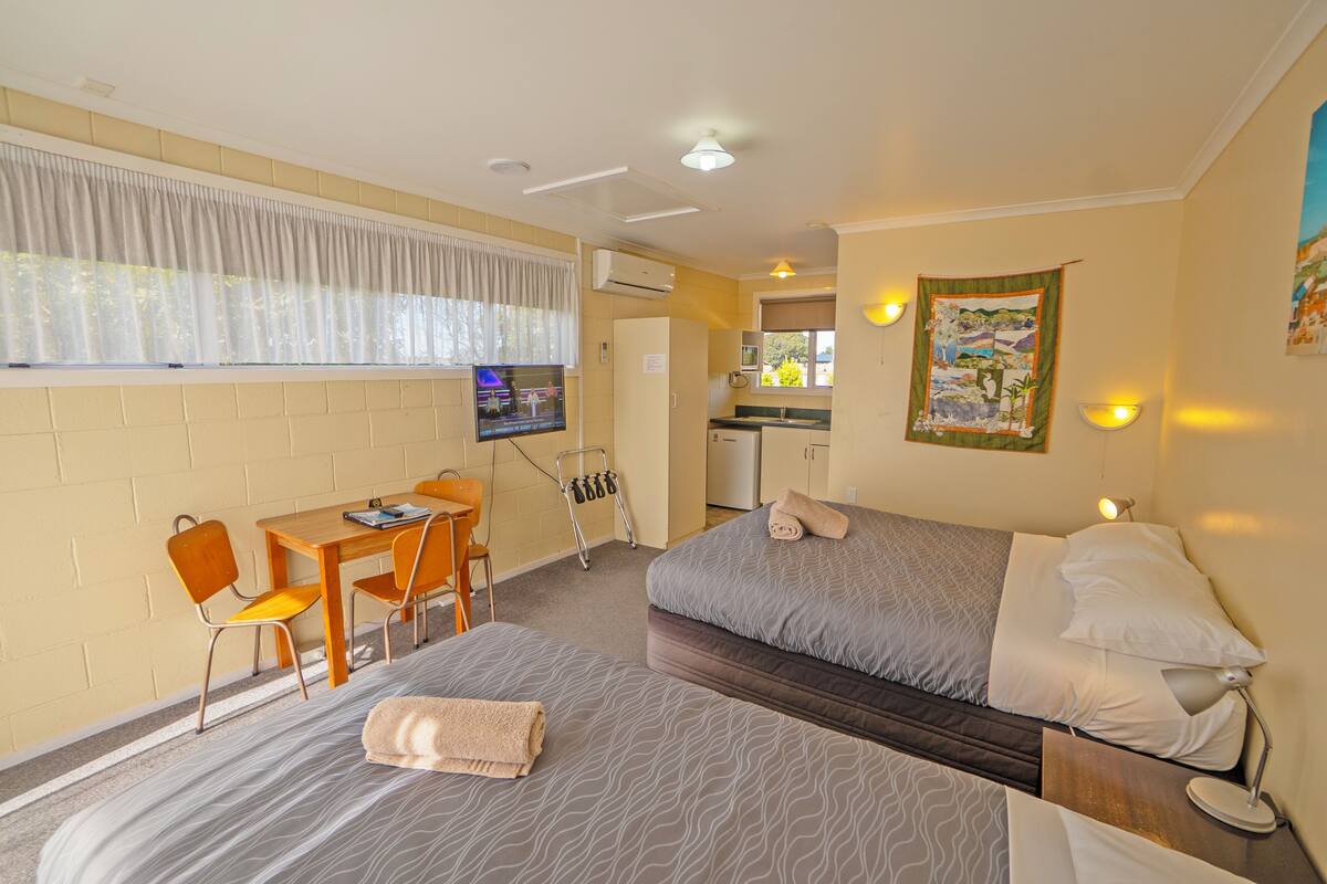 Quarto de hotel com duas camas, uma escrivaninha e uma cadeira.