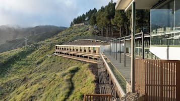 Um edifício moderno com fachada de vidro e vista para uma paisagem montanhosa.