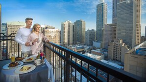 Um casal jantando em uma varanda com vista para a cidade.