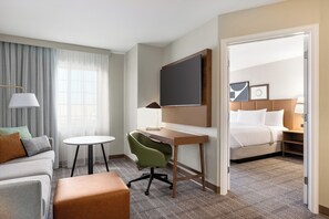 Quarto de hotel com escrivaninha, cadeira, sofá e cama.