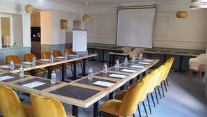 Uma sala de conferência com uma mesa comprida, cadeiras amarelas, garrafas de água e um quadro branco.