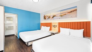 Quarto de hotel com duas camas, uma parede azul de destaque e uma janela grande.