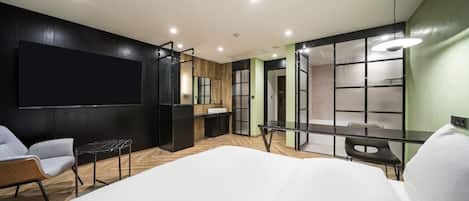 Quarto de hotel moderno com uma cama grande, uma mesa, uma cadeira e um espelho.