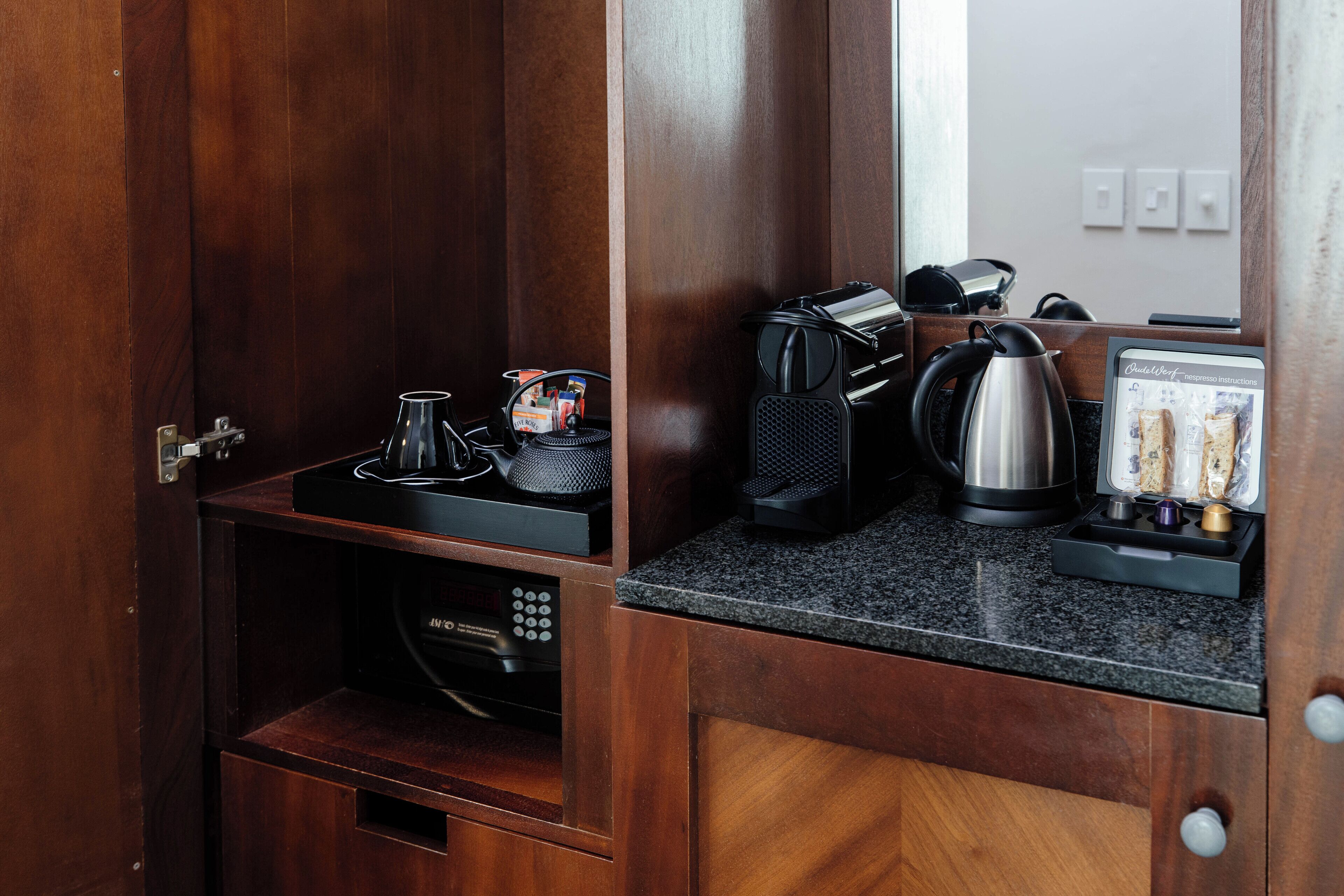 Uma cozinha compacta com cafeteira, chaleira e um pequeno frigorífico.