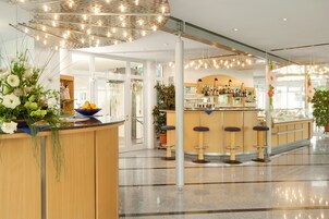 Uma área de bar moderna com bancada de granito polido, vários bancos e uma variedade de garrafas e copos.