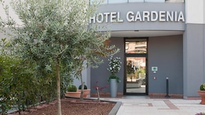 Exterior do Hotel Gardenia, com fachada moderna, entrada acolhedora e área de jardim ajardinada.