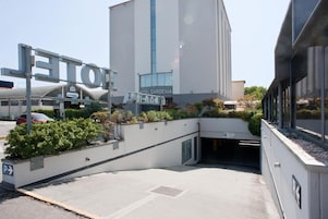 Entrada moderna de hotel com placa indicando 'HOTEL GARDENIA' e área de estacionamento.