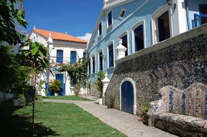 Um pátio com um banco azulejado, uma porta azul e um edifício branco com um muro de azulejos.