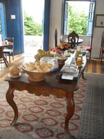 Um buffet de café da manhã com diversos alimentos e bebidas sobre uma mesa de madeira.