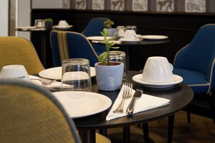 Uma mesa de jantar posta com pratos, talheres, uma xícara e um vaso de planta.