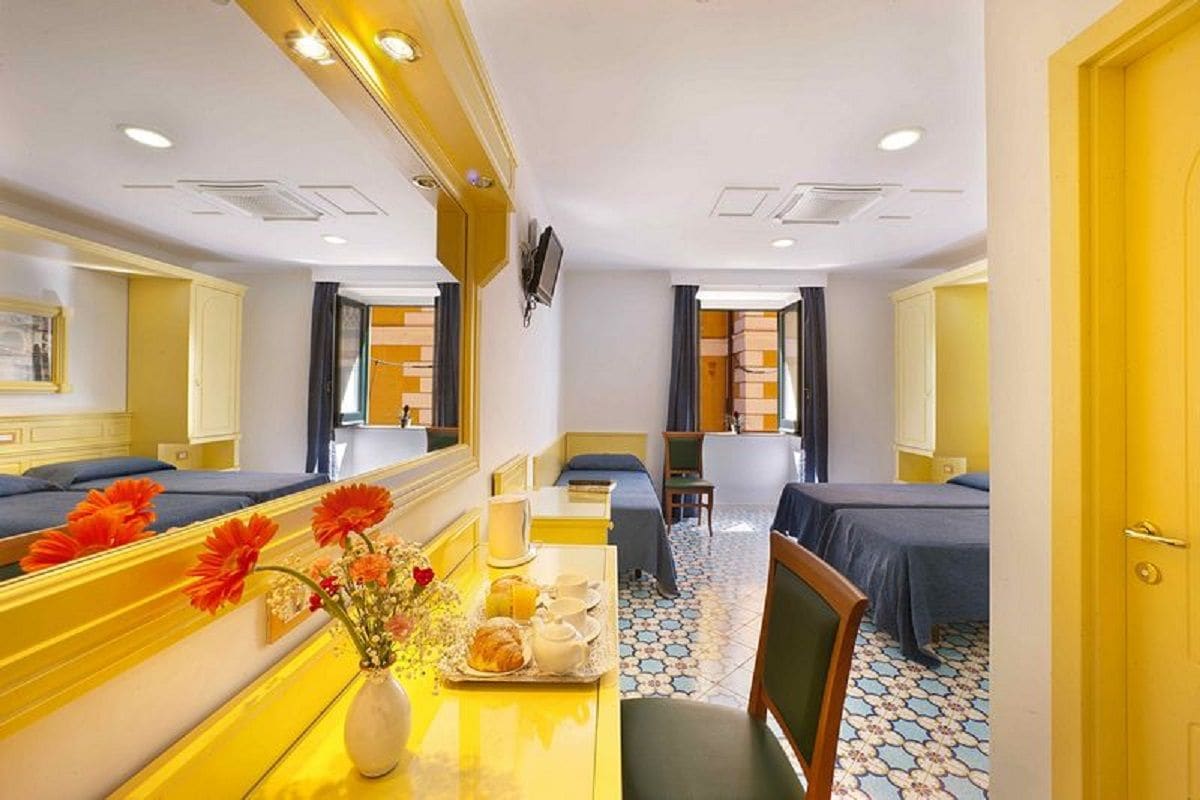 Quarto de hotel com duas camas, uma mesa de jantar com café da manhã, um espelho e uma televisão.