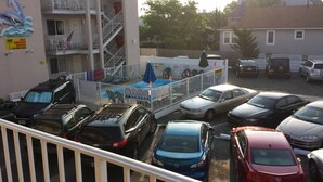 Um motel de vários andares com piscina no térreo, rodeado por carros estacionados.