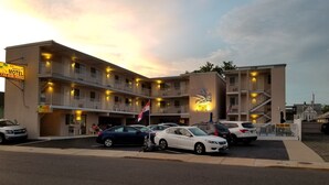 Um motel com vários andares, estacionamento externo e um mastro com uma bandeira.