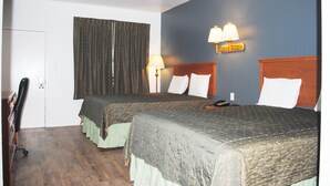 Quarto de hotel com duas camas, uma escrivaninha e uma cadeira.