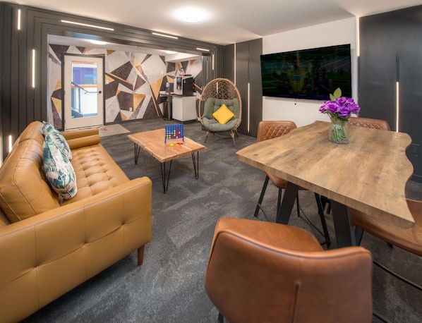 Uma sala de estar moderna com um sofá, cadeiras, uma mesa de centro e uma mesa de jantar.