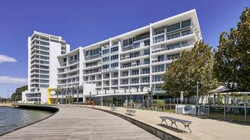 Um hotel moderno de vários andares, com varandas, calçadão à beira-mar e áreas de estar ao ar livre.