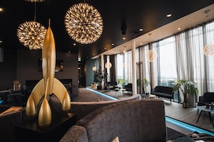 Um hall de hotel moderno com balcão de recepção, área de estar e grandes janelas.