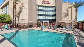 Um hotel com piscina, área de estar externa e palmeiras.