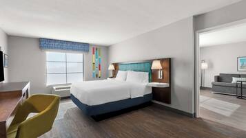 Quarto de hotel moderno com uma cama grande, uma escrivaninha, uma cadeira e um sofá.