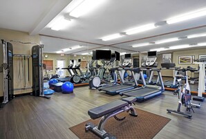 Uma academia com esteiras, bolas de exercício e máquinas de peso.