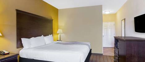 Quarto de hotel com uma cama grande, mesas de cabeceira, cômoda e televisão na parede.