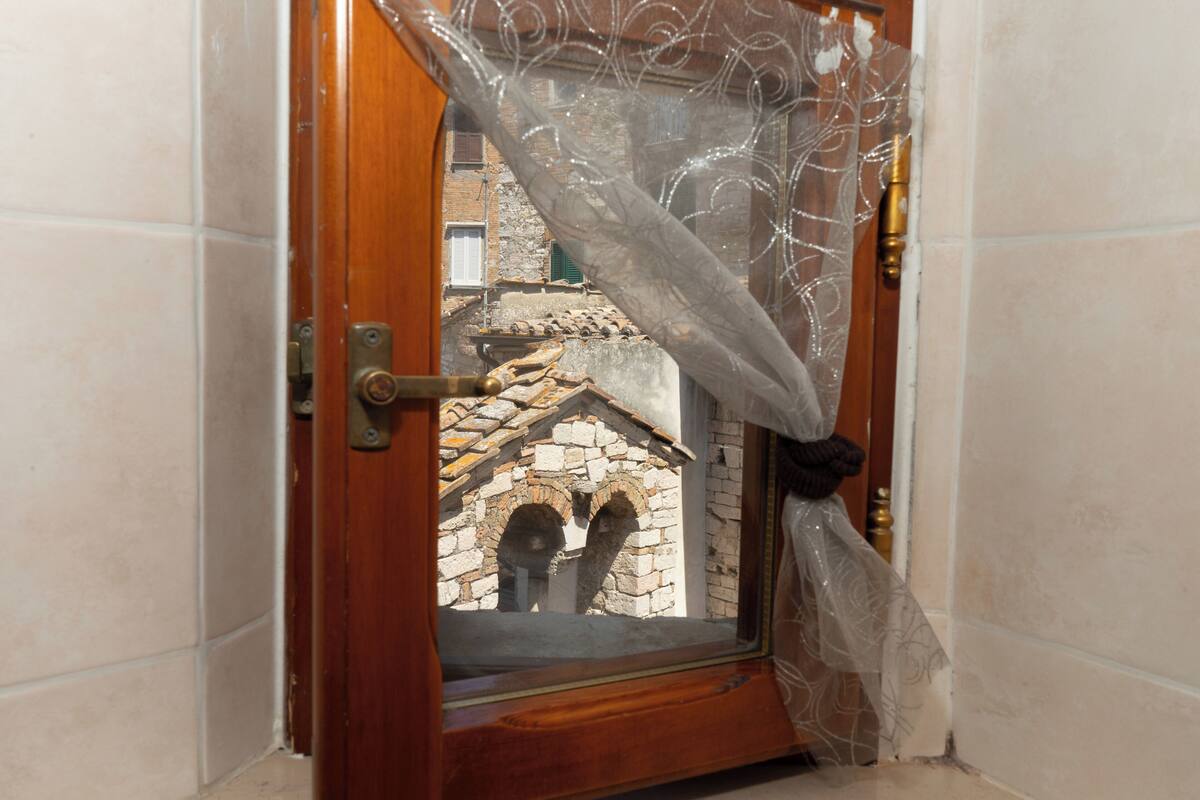 Uma porta de madeira com um painel de vidro, puxador de metal e uma chapa de fechadura de ferro decorativa.