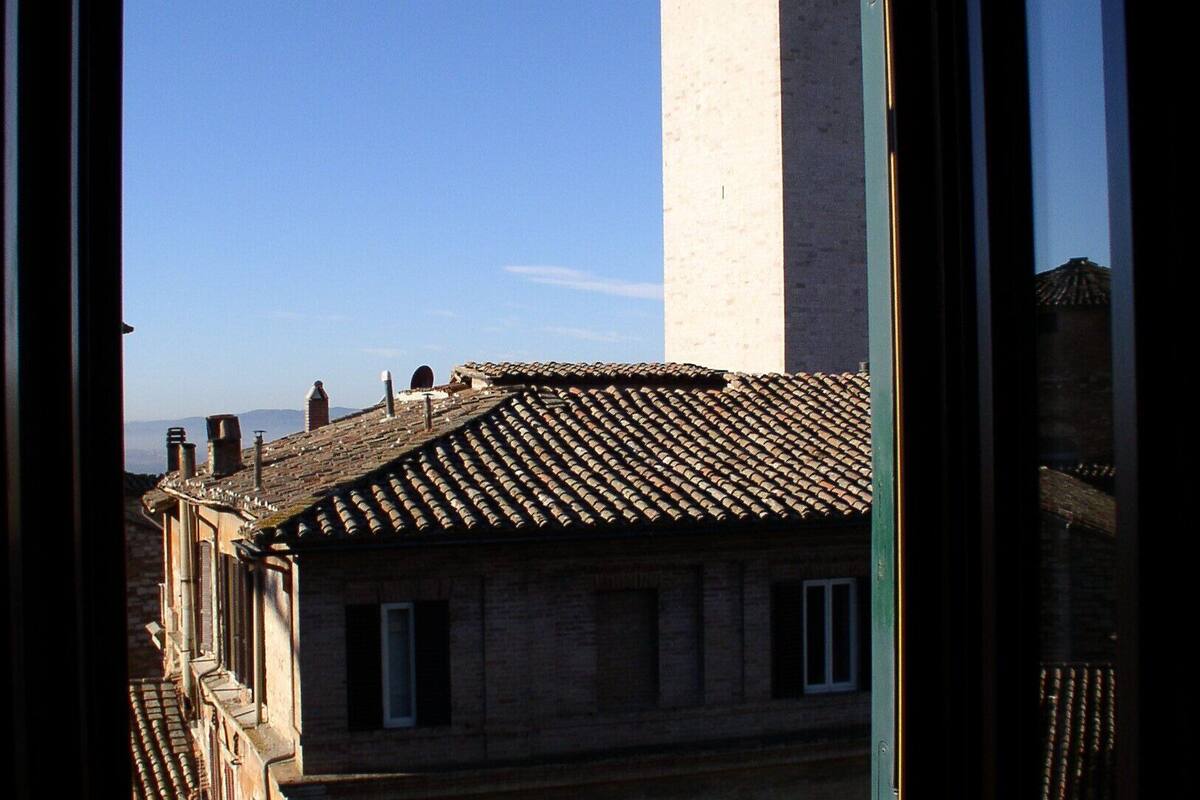 Vista de um edifício alto com fachada branca e céu azul límpido.