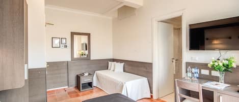 Quarto de hotel com duas camas, uma escrivaninha, uma cadeira, uma televisão e porta do banheiro.