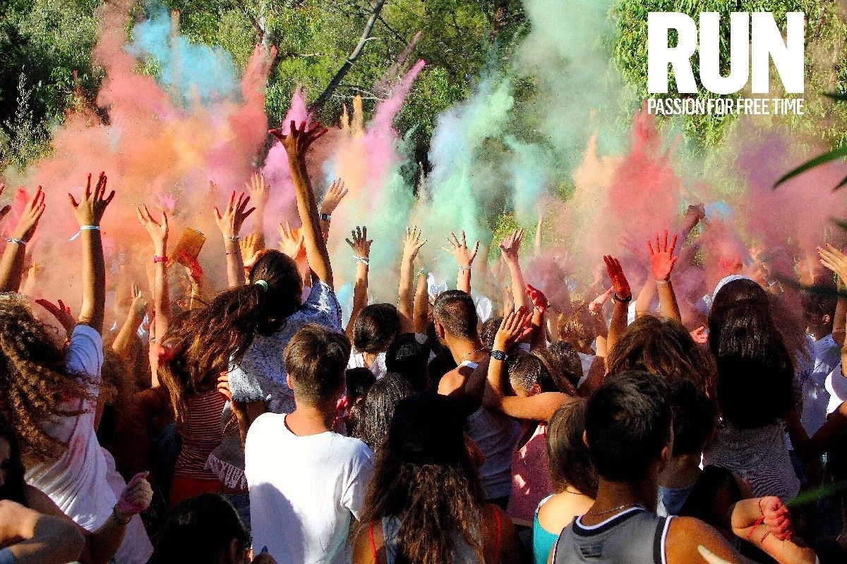 Um grupo de pessoas em um evento ao ar livre, com as mãos levantadas e fumaça colorida no ar.