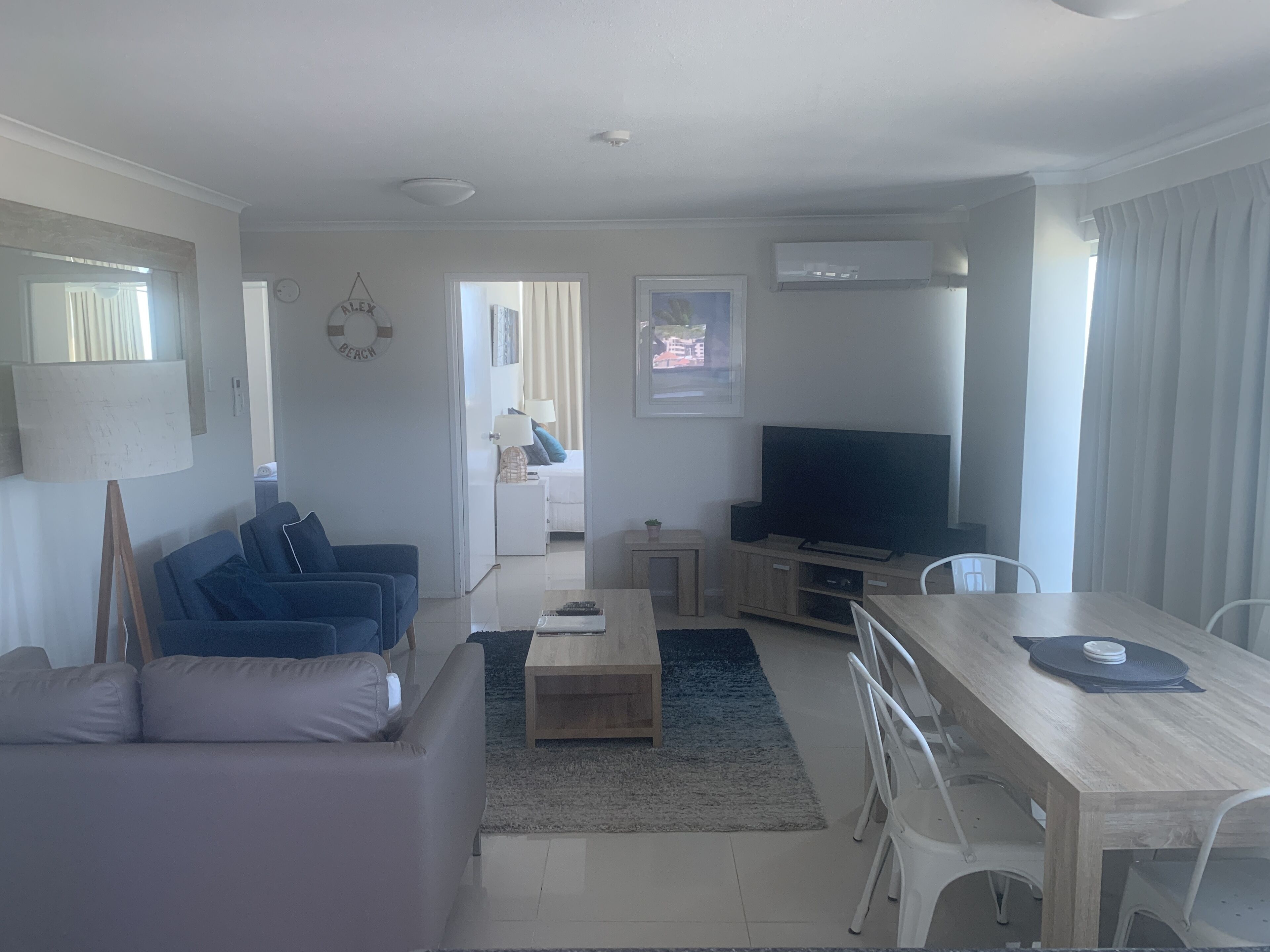 Uma sala de estar moderna com sofá, mesa de centro, televisão e área de jantar.