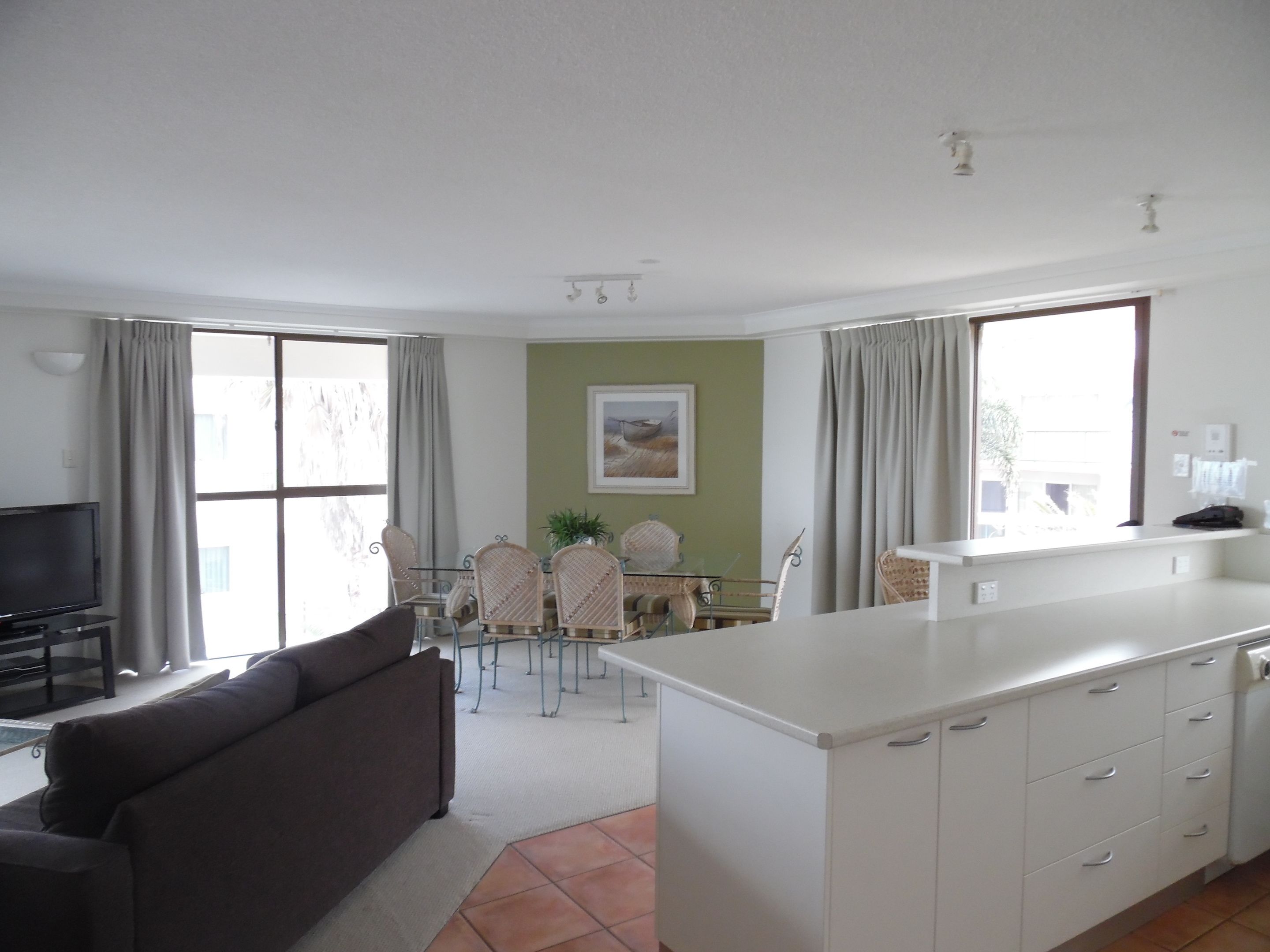 Uma sala de estar moderna com sofá, mesa de jantar, cadeiras e televisão.