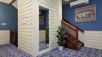 Quarto com chão azul estampado, escada de madeira e espelho refletindo o ambiente.