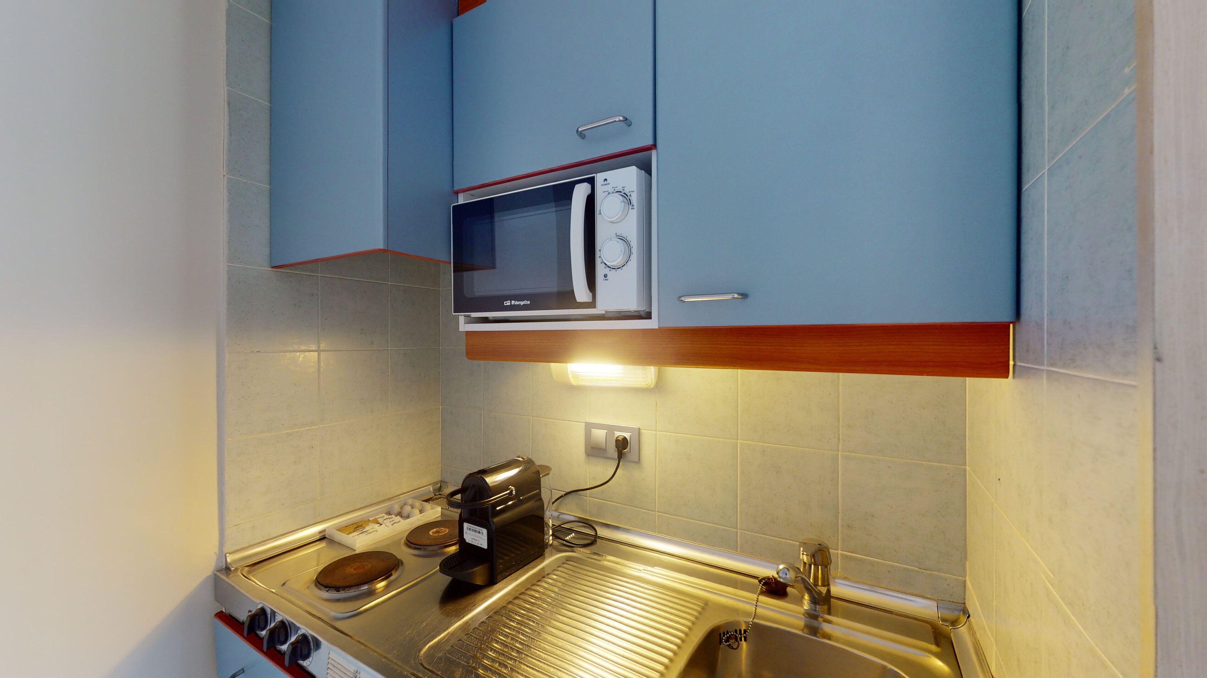 Cozinha compacta com fogão, micro-ondas e pia.