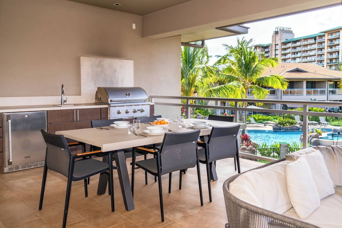 Varanda com mesa de jantar, cadeiras, churrasqueira e vista para a piscina.