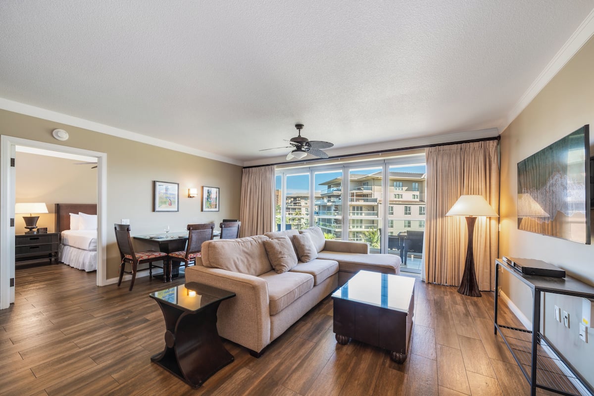 Quarto de hotel moderno com sofá, mesa de centro e área de refeições.