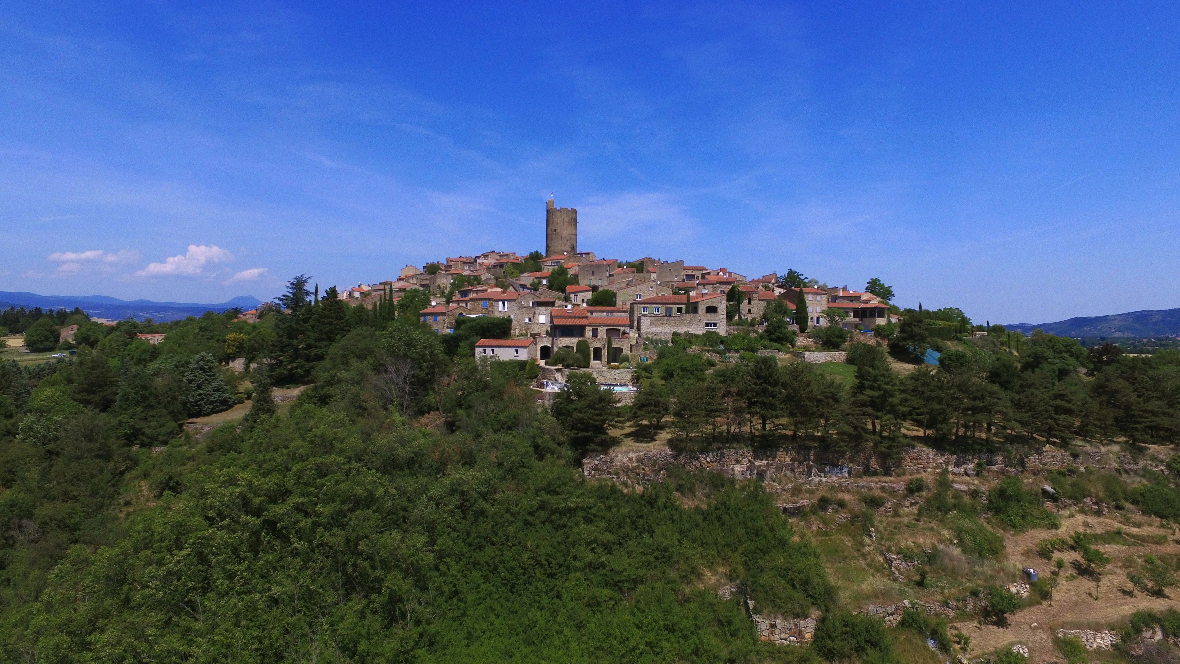 Uma cidade histórica com uma torre imponente, rodeada por vegetação exuberante e arquitetura tradicional.