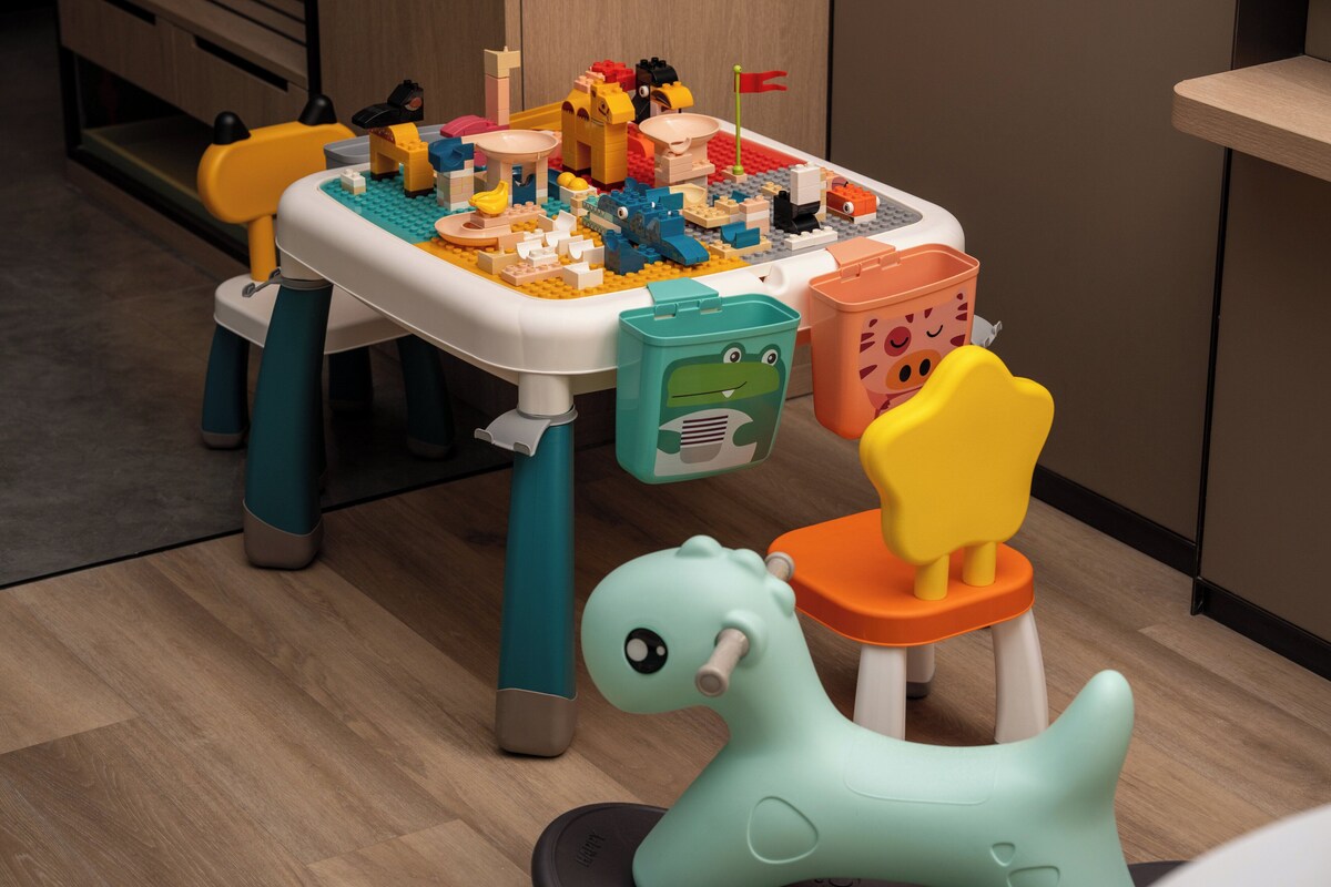 Espaço infantil com mesa, cadeiras e um dinossauro de brinquedo.