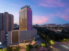 Um hotel com várias andares e fachada curva característica, com um letreiro no terraço.