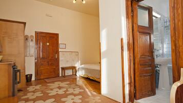 Quarto com cama, porta de madeira e banheiro visível por uma porta aberta.