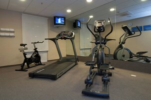Uma academia com esteiras, bicicletas ergométricas e um elíptico.
