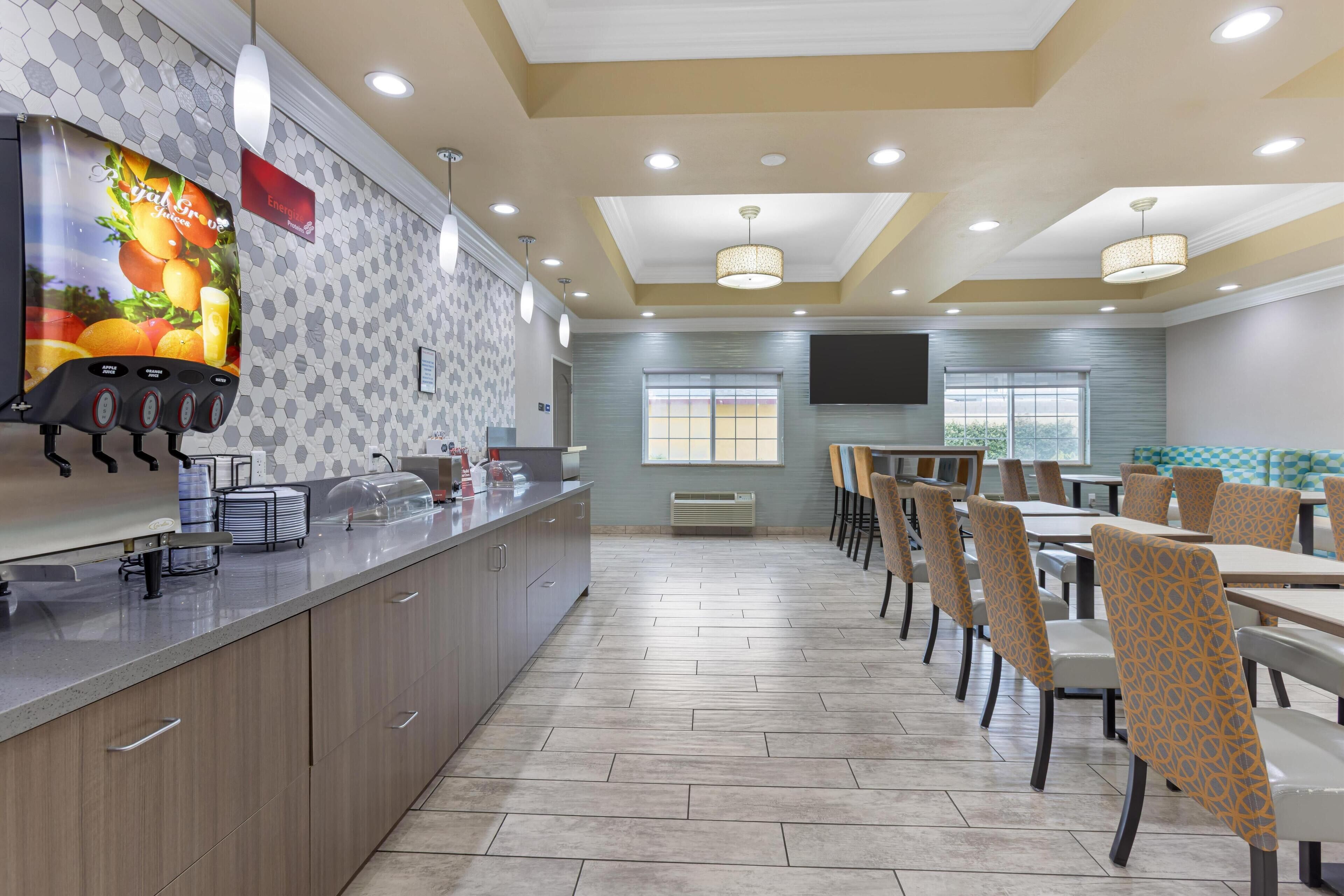 Uma cafeteria moderna com um balcão comprido, área de estar e uma tela grande exibindo um anúncio de bebida.