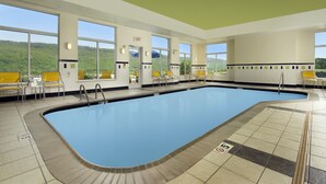 Piscina com cadeiras amarelas e janelas amplas.
