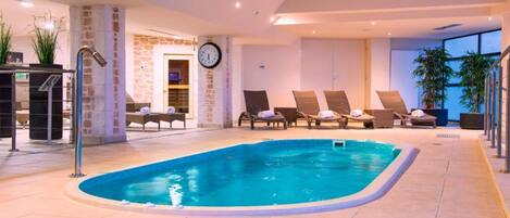 Uma piscina interior com espreguiçadeiras e um relógio na parede.