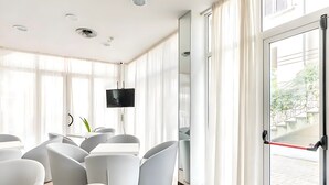 Quarto de hotel moderno com área de refeições, televisão de tela plana e uma grande janela com cortinas.
