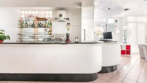 Uma área de bar moderna com balcão curvo, prateleiras com garrafas e uma máquina de café.