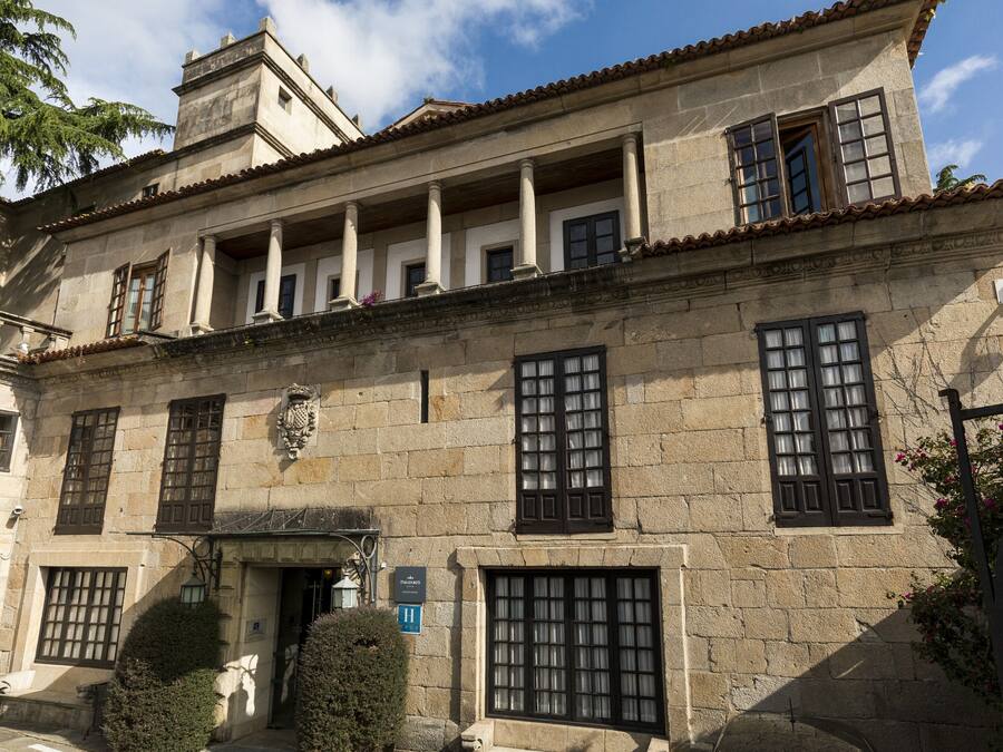 Um edifício histórico com fachada simétrica, janelas grandes e entrada central.