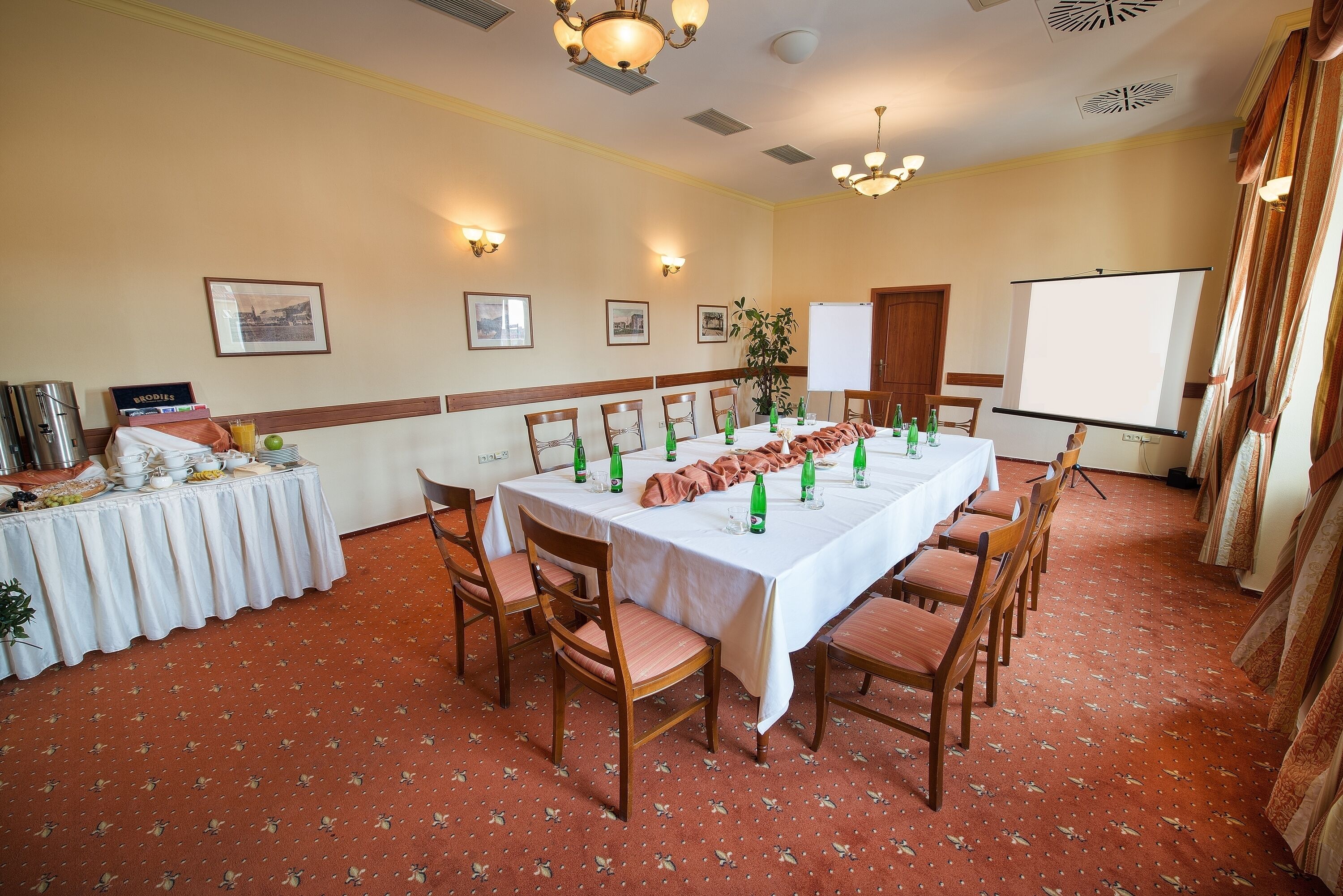 Uma sala de conferências com uma mesa comprida, cadeiras, um quadro branco e quadros nas paredes.