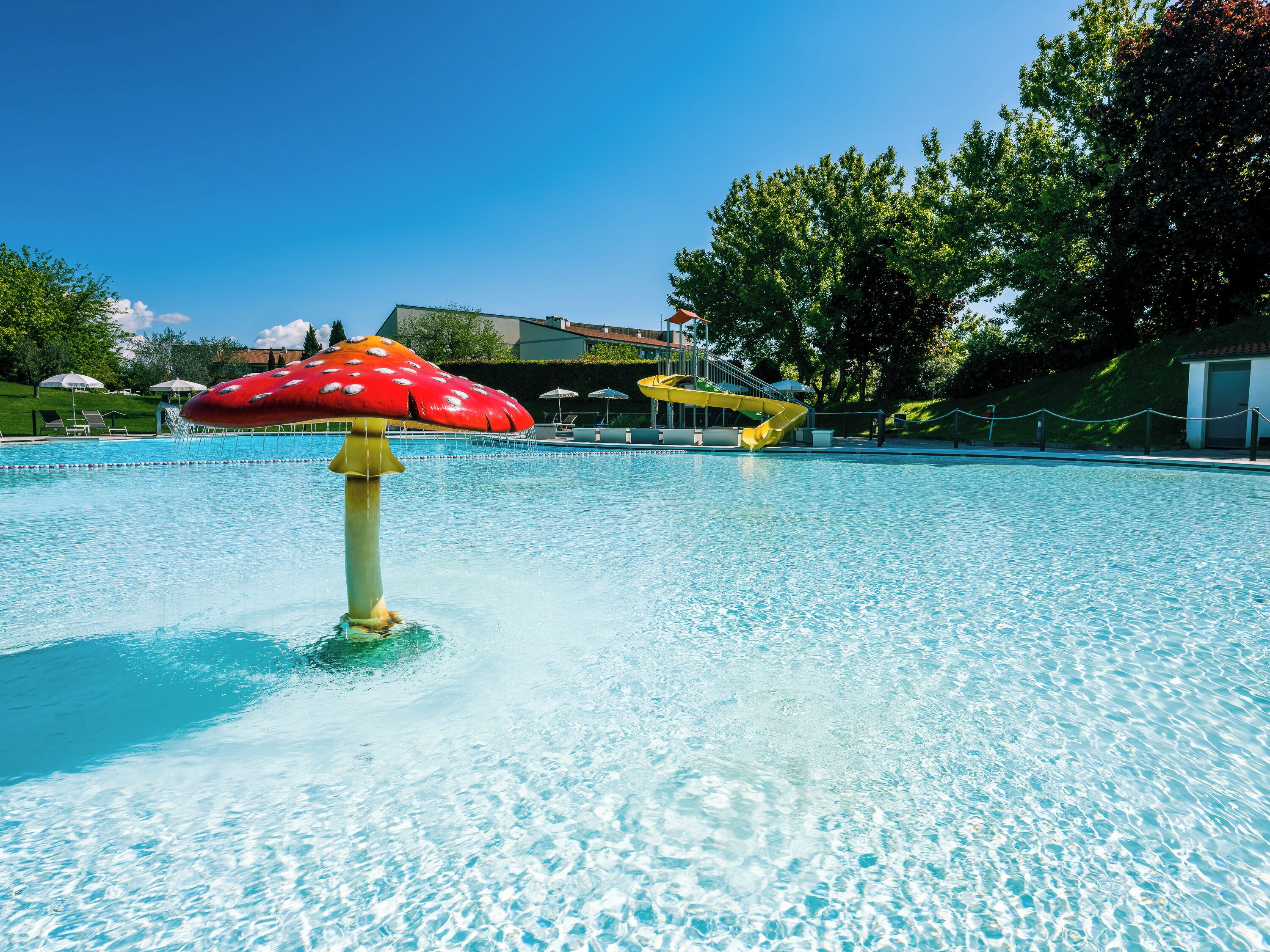 Uma piscina com um espelho d'água em formato de cogumelo e um escorregador.